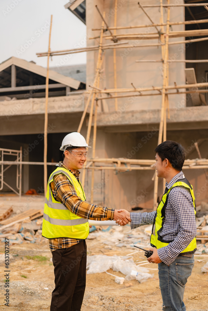 Two Asian male engineers shaking hands and working together Hope stands ...