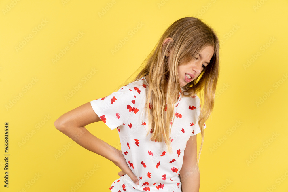 blonde kid girl wearing polka dot shirt over yellow studio background ...