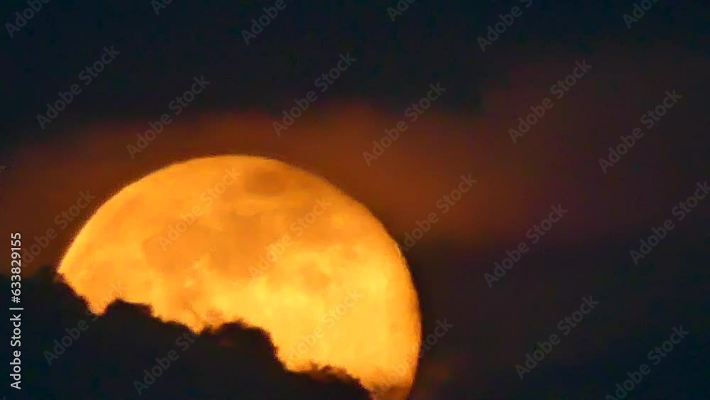 Orange and yellow moon with atmospheric refraction distorting disk of ...