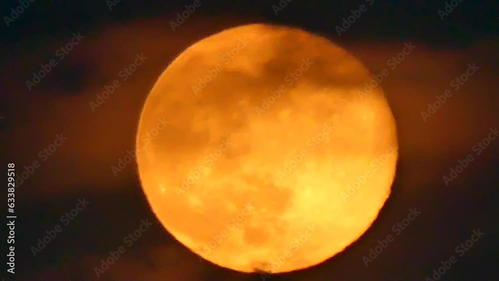 Orange and yellow moon with atmospheric refraction distorting disk of ...