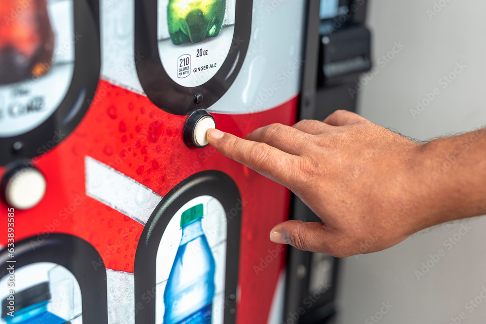 A man selects a beverage from a cold soda vending machine. Pressing a ...