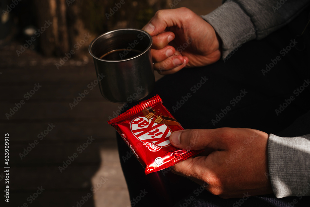 A man holding a Kit Kat bar and a mug of hot coffee Stock Photo | Adobe ...