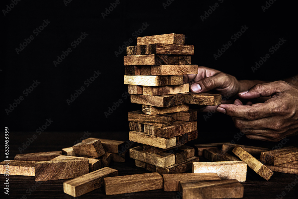 Hand placing wooden block stack in pyramid falling caution to prevent ...