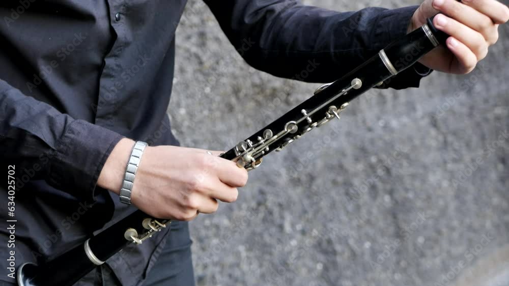 A young musician prepares a clarinet for a performance by assembling ...