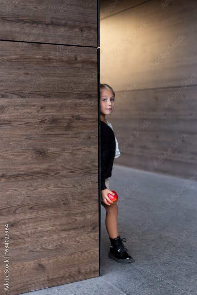 Back to school outdoor. A cute girl is holding a red apple. Primary ...