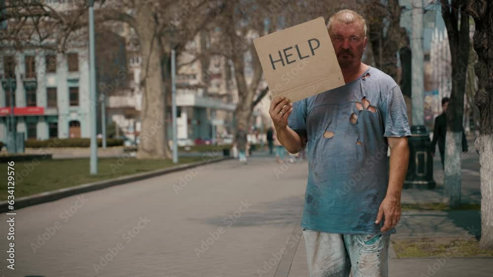 Homeless dirty adult man in old torn clothes stands on city street ...