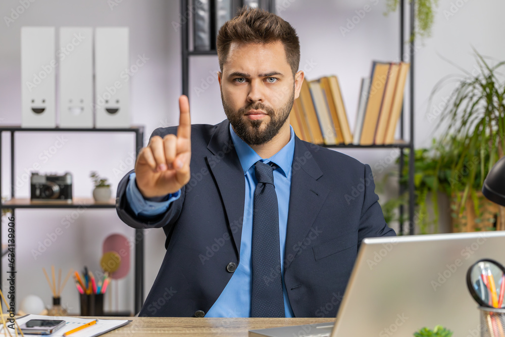 Caucasian young businessman working on laptop computer shakes finger ...