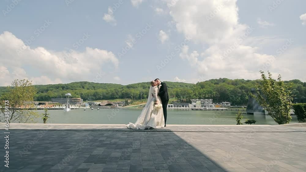 Groom Kissing and Embracing Beloved Bride near Lake. Happy Newlyweds in ...