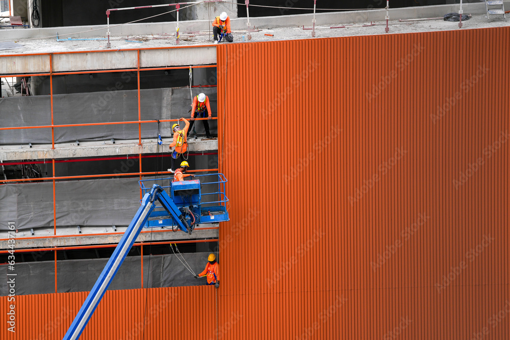 workers install material of metal wall on facade structure building ...