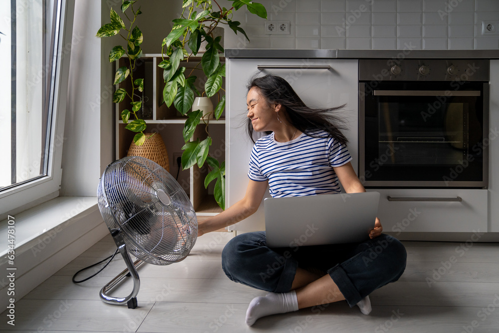 Woman turned powerful electric fan sitting cross-legged on floor in ...