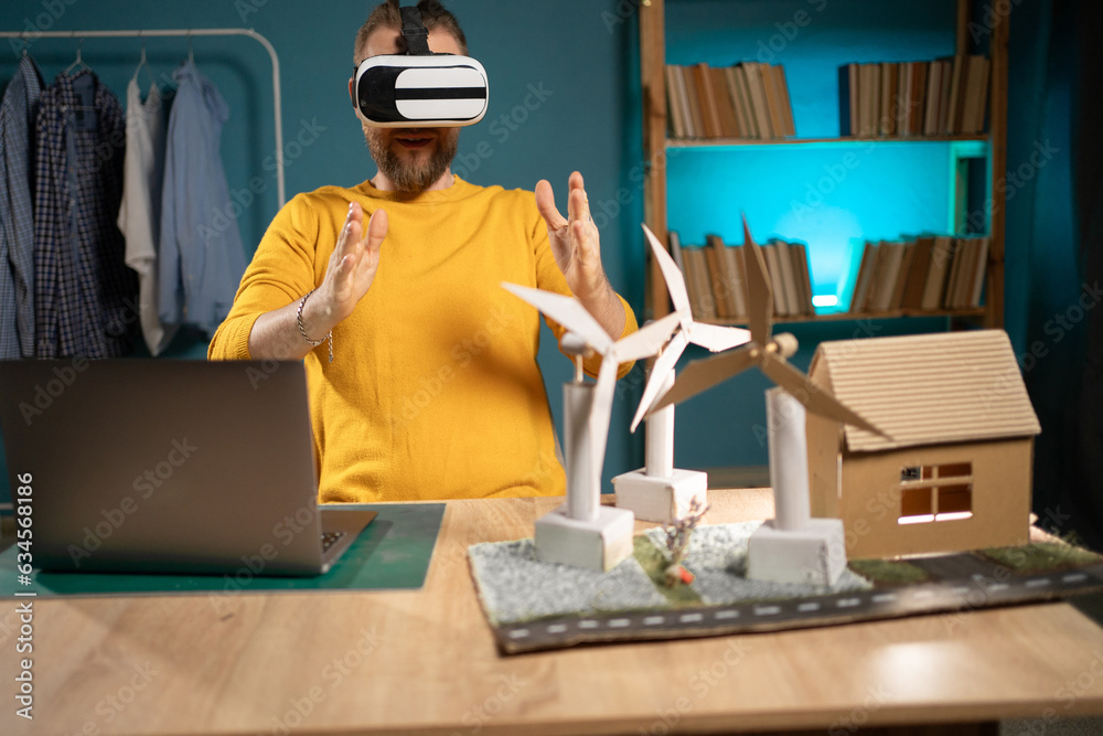 Young man making renewable energy project dummy using laptop and vr ...