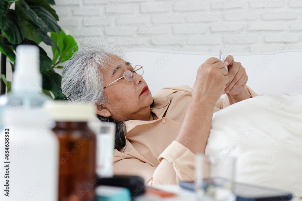 Elderly woman lying sick on the couch taking medicine. The concept of ...