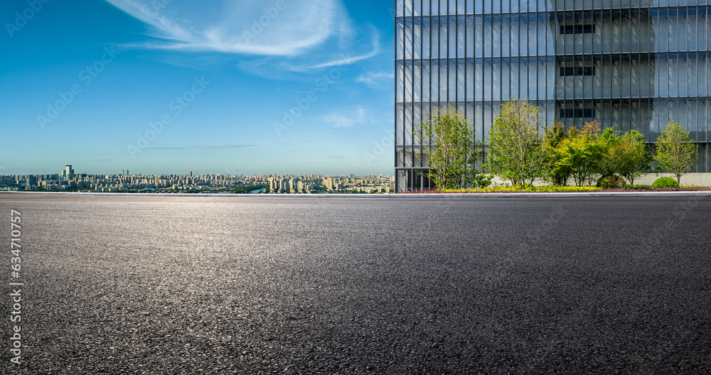 Asphalt road and glass wall architecture with city skyline background ...
