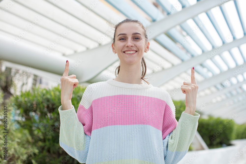 pretty woman feeling awed and open mouthed pointing upwards with a ...