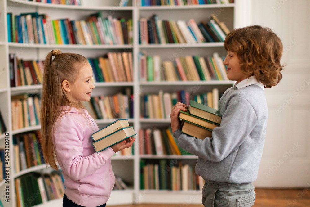School boy and girl holding stack of books and talking with each other ...