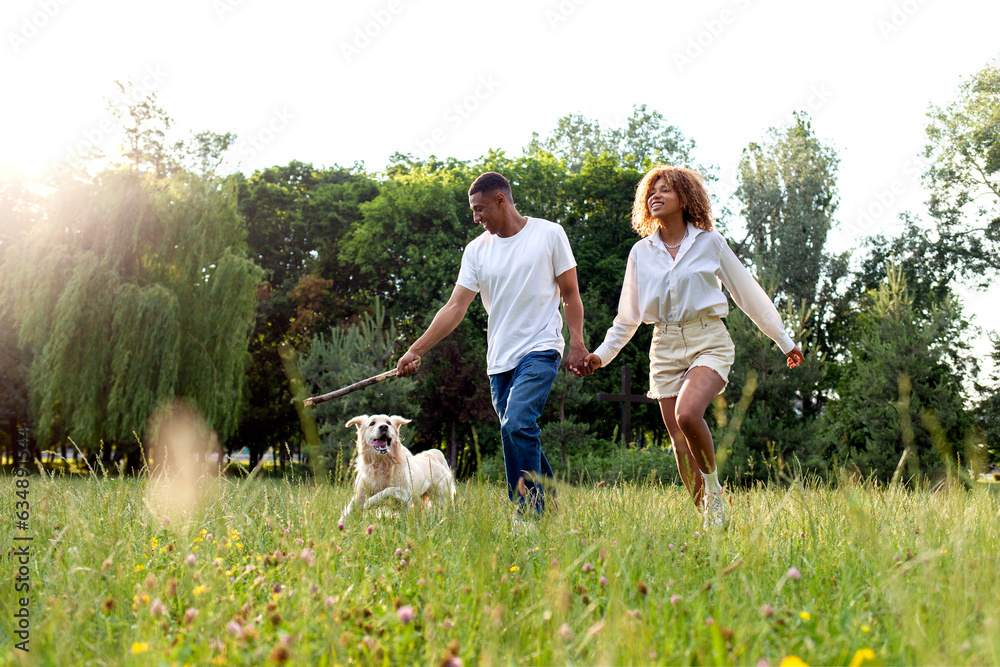 african american happy couple walk and run together with dog in park in ...