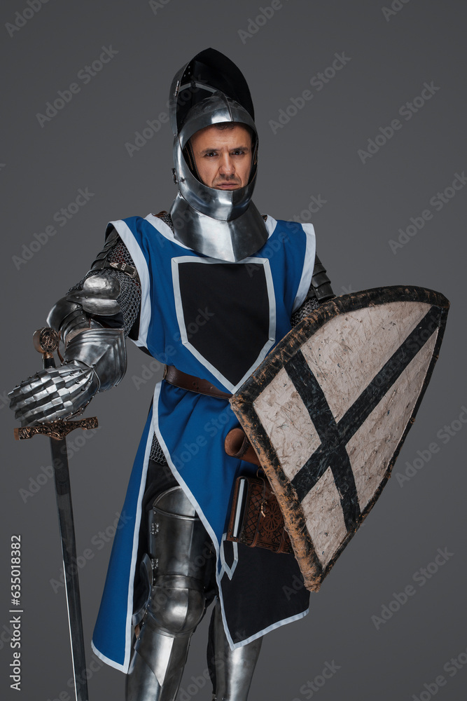 Valiant medieval warrior wearing armor and blue surcoat with raised ...