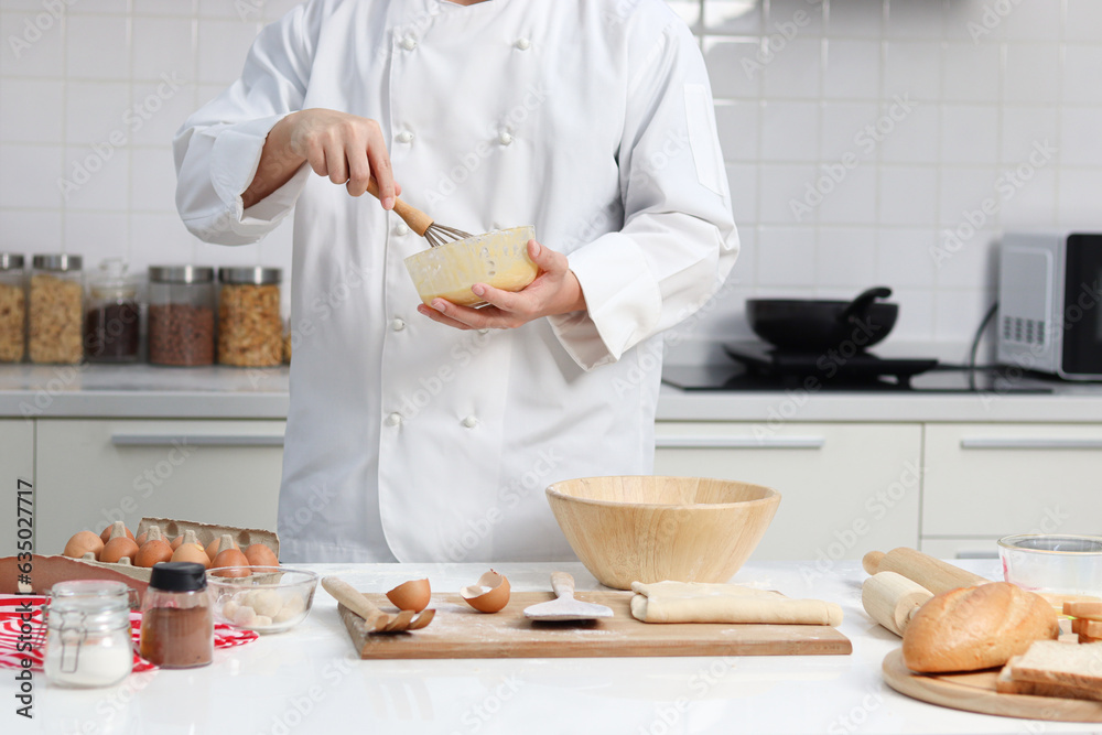 Happy smiling Asian man in white chef uniform with hat, stirring and ...