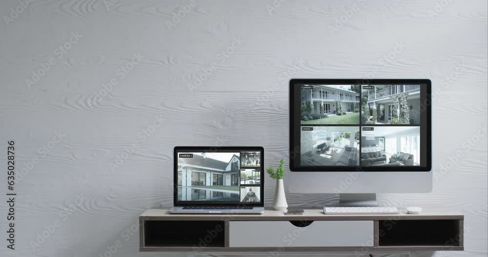 Wall mounted computer monitor and laptop on desk with security camera ...