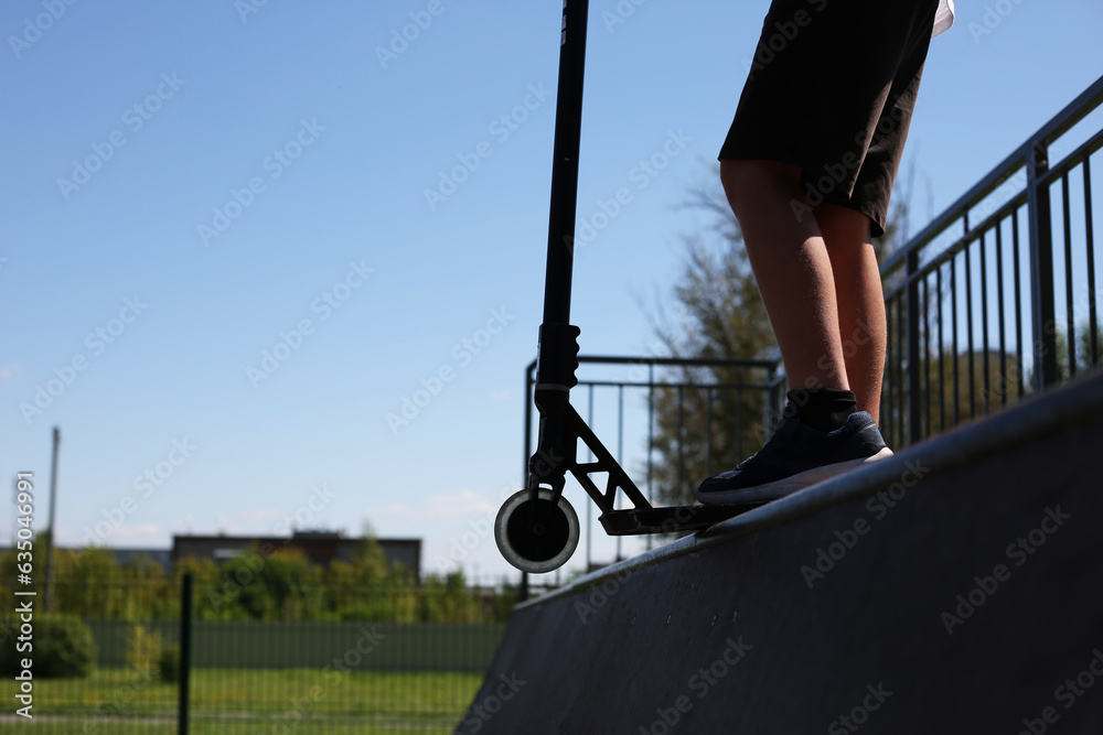 Scooter and boy's legs on top of ramp getting ready for jump in skate ...