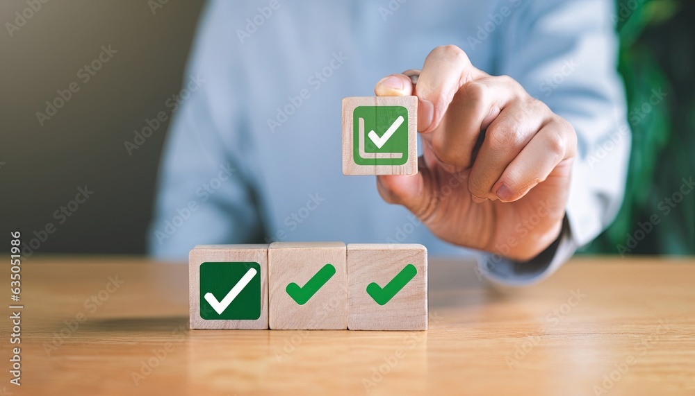 Wooden blocks checklist and green check mark icon with hand on table ...