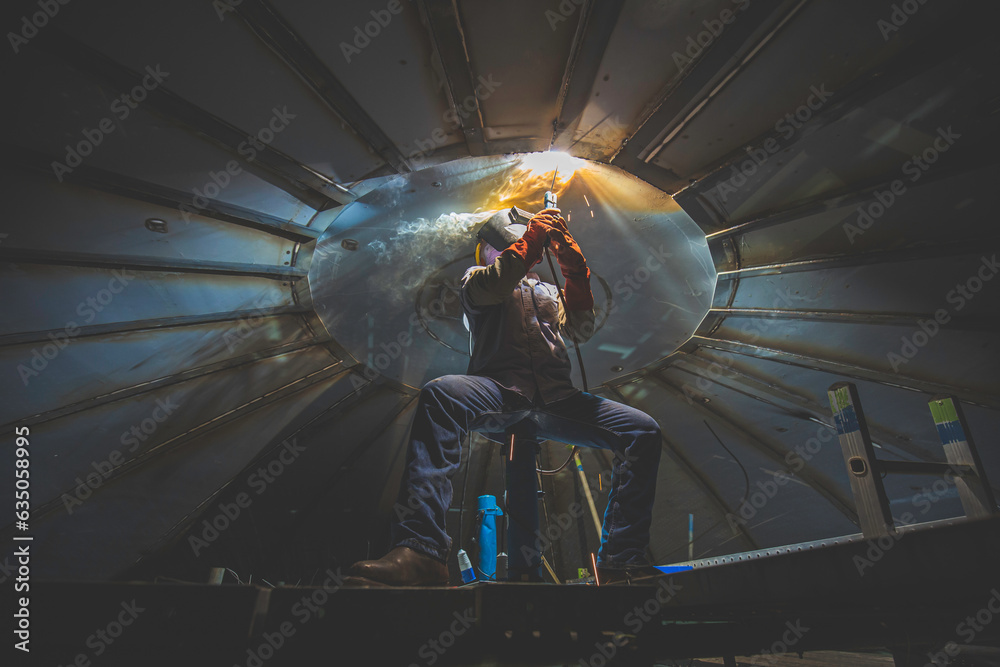 Welding male worker metal arc is part roof tank dome inside confined ...