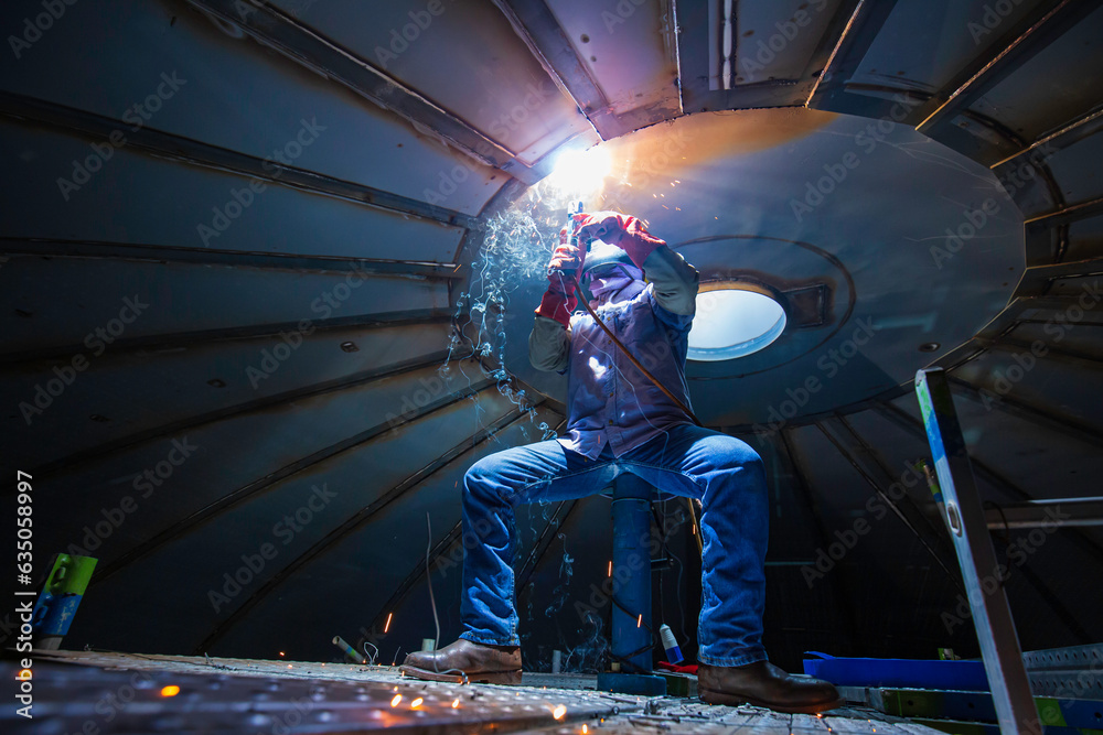 Welding male worker metal arc is part roof tank dome inside confined ...
