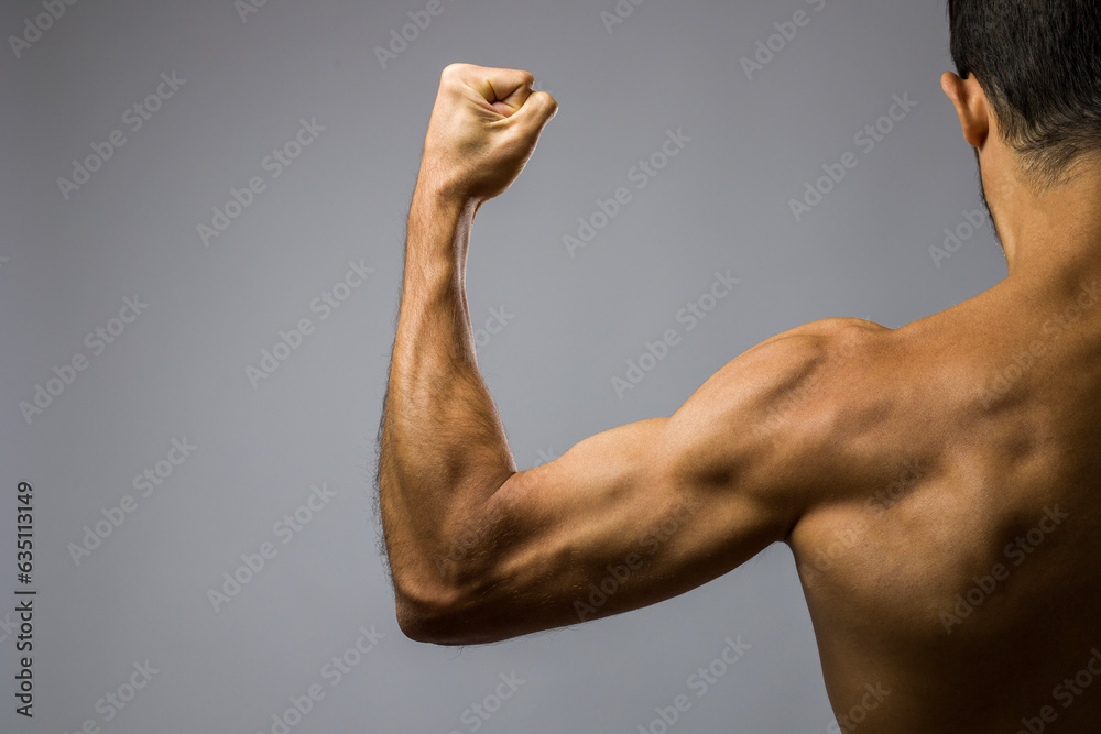 Muscular man showing muscles isolated on grey background. Biceps and ...