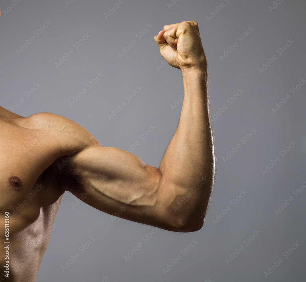 Muscular man showing muscles isolated on grey background. Biceps, chest ...