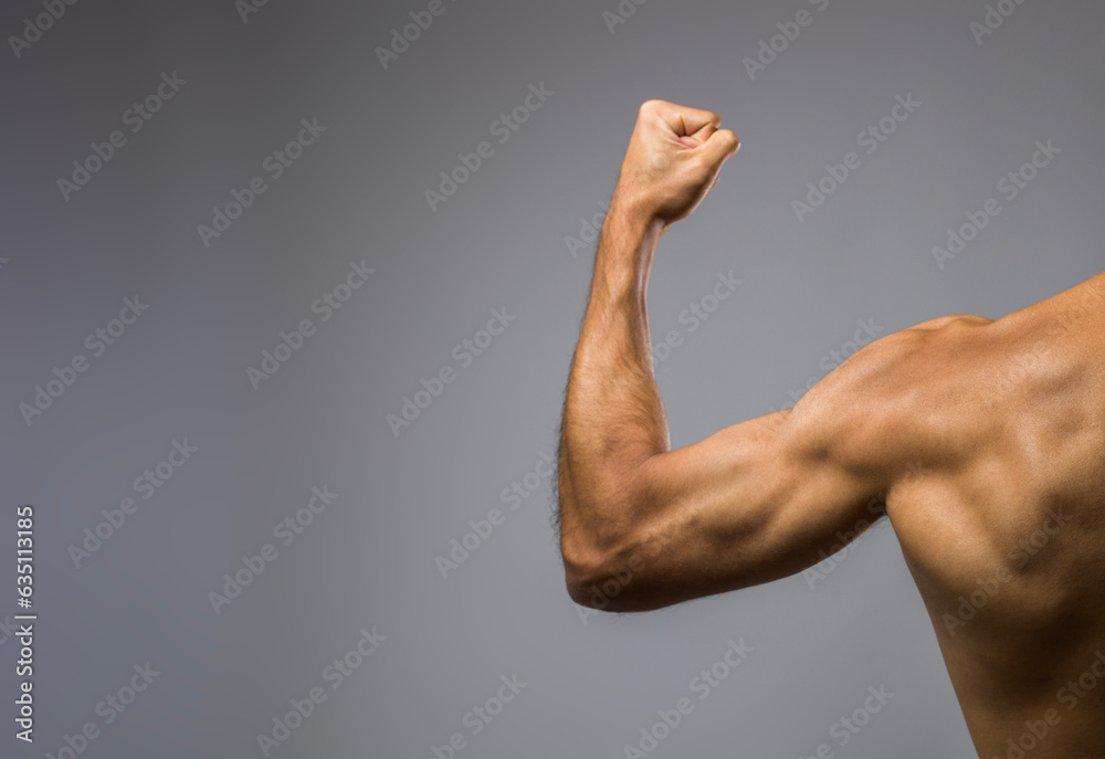 Muscular man showing muscles isolated on grey background. Biceps and ...