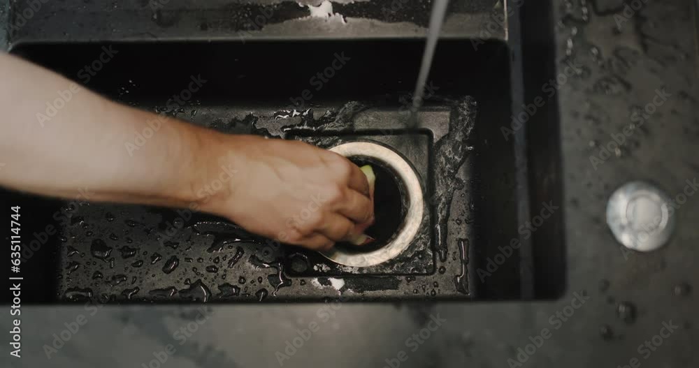 Man throwing food waste into the garbage disposal in the kitchen sink ...
