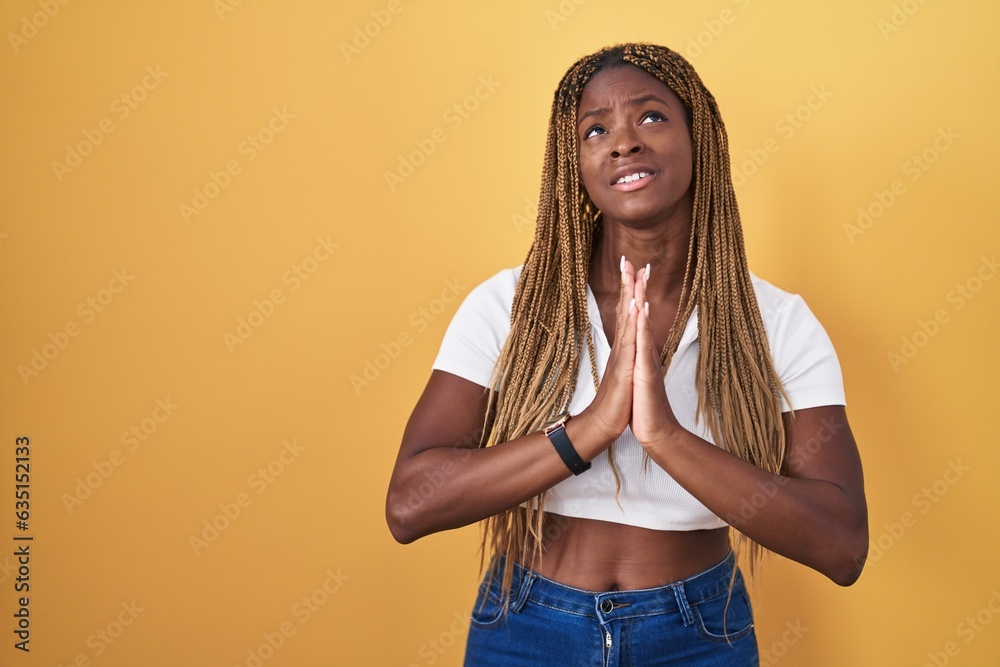 African american woman with braided hair standing over yellow ...