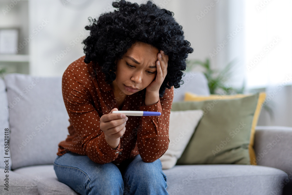 Frustrated and sad young african american woman crying sitting on sofa ...