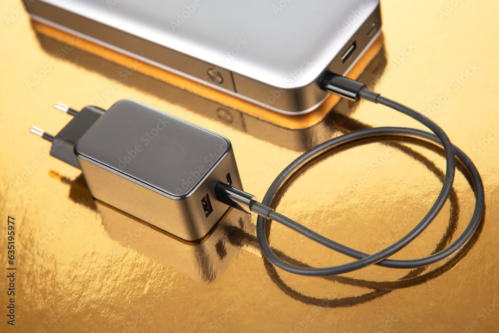Power bank and charging plug with cable on a golden background ...