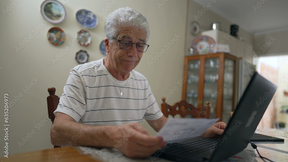 Worried senior man looking at fine paper in front of laptop computer ...