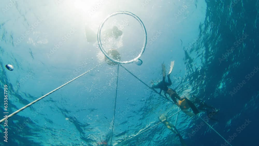 Freediving on the rope in a sea. Male freediver dives through the ring bubble with monofin vídeo ...