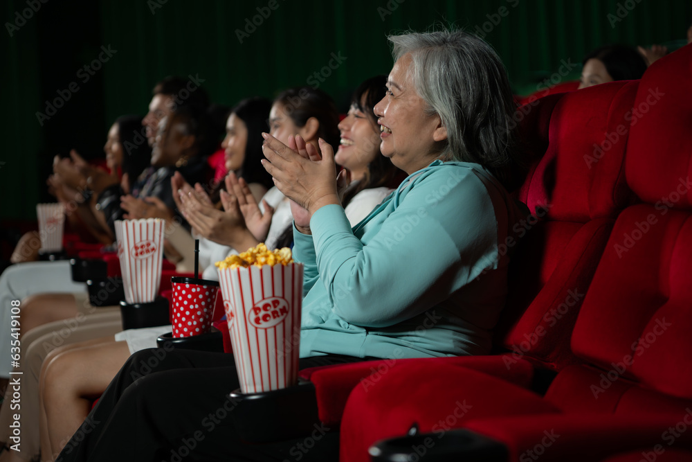 Family members of an Asian senior woman clap their hands for the movies ...