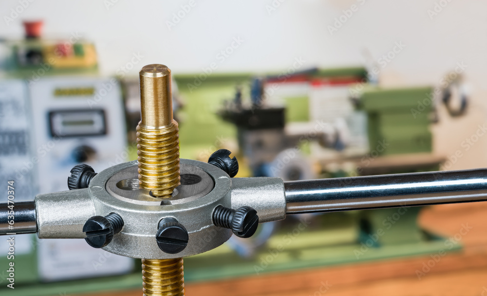 Closeup a steel metalworking die at cutting screw thread on a brass rod ...