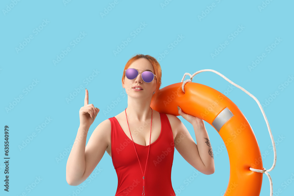 Female lifeguard with ring buoy pointing at something on blue ...