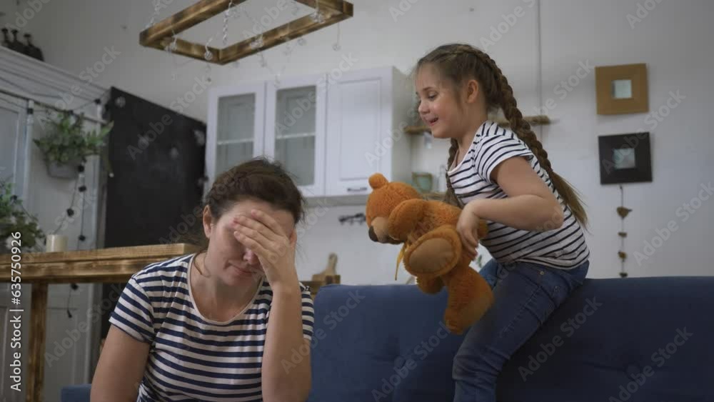 Irritated girl with sore head. Daughter screams and plays with teddy ...