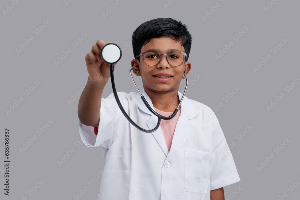 Indian Asian kid boy aged 7 to 8, wearing a doctor apron with holding ...