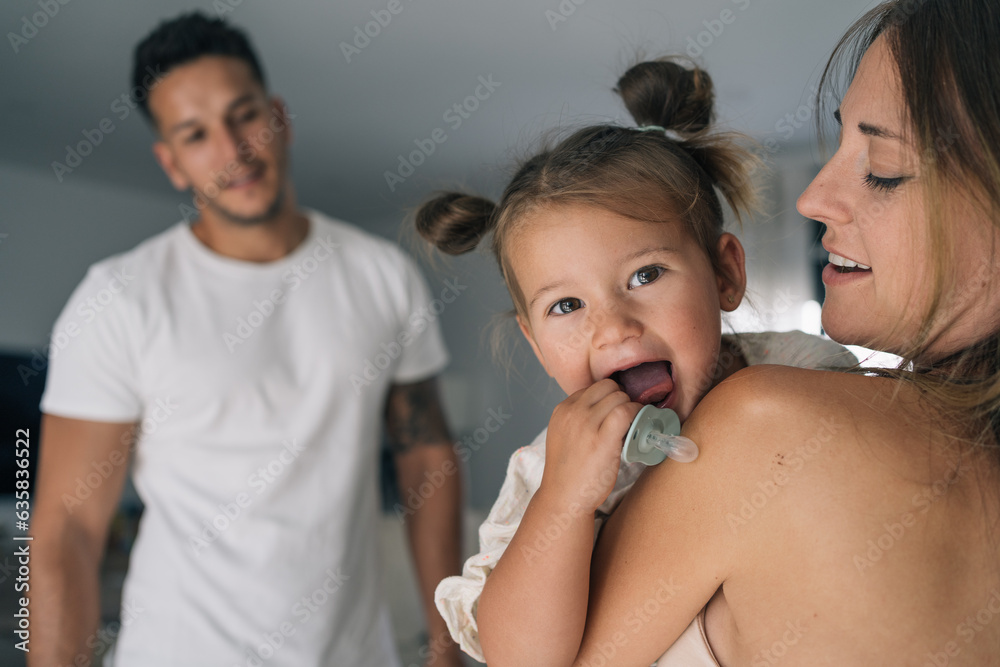 Portrait of a little girl with two lock of hair and pacifier sticking ...