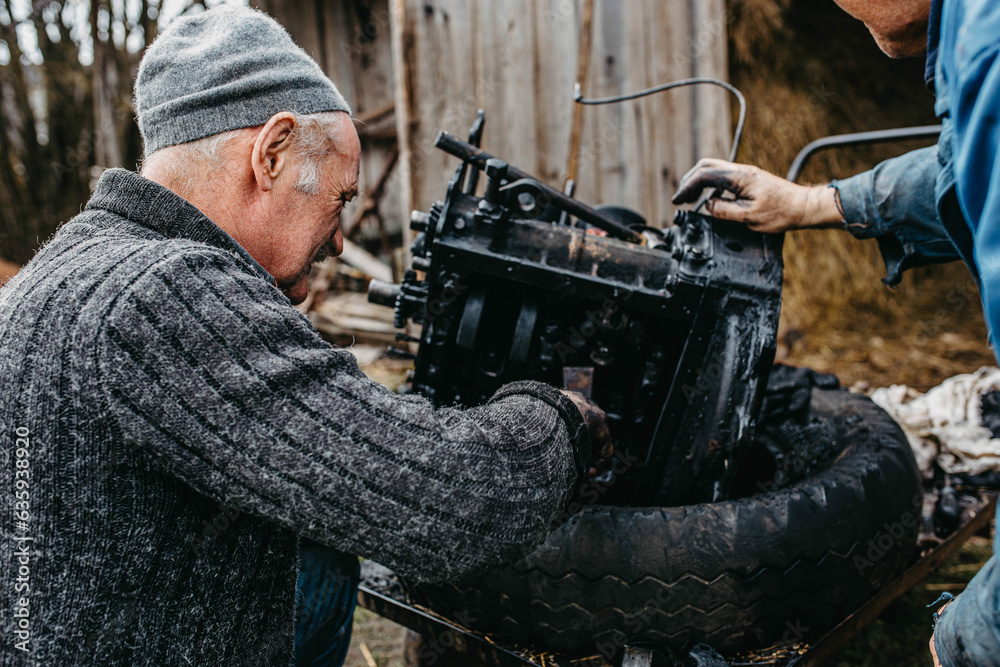 elderly man tuning a car engine at home in a garage, customizing an ...