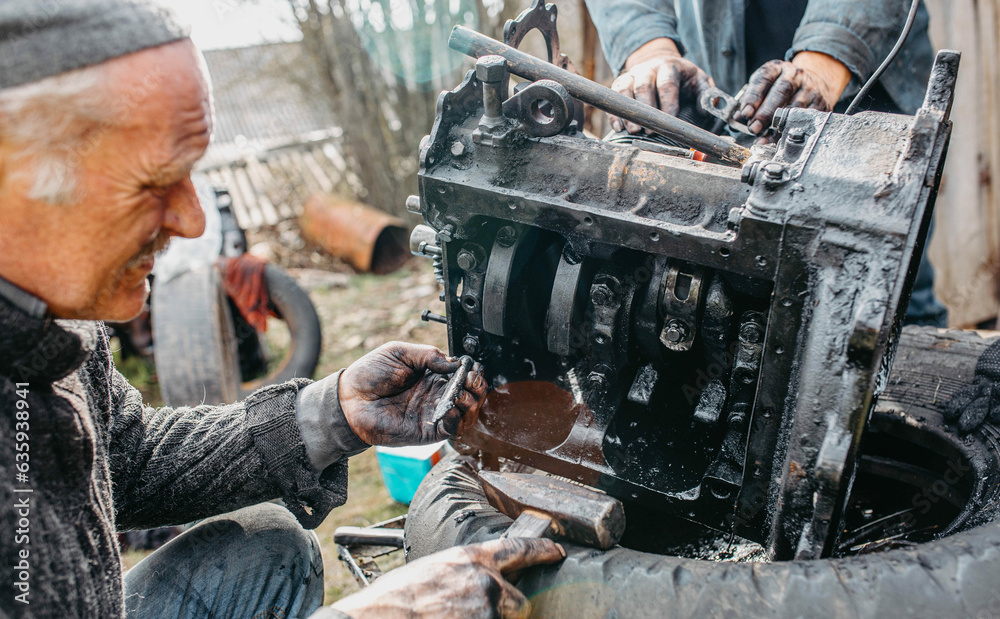 elderly man tuning a car engine at home in a garage, customizing an ...