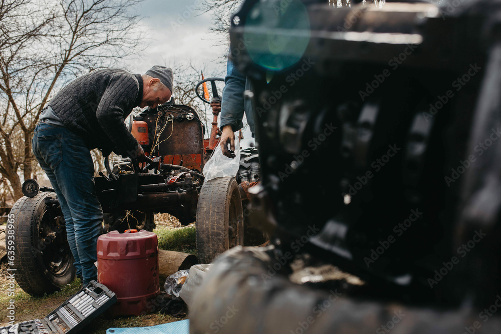 elderly man tuning a car engine at home in a garage, customizing an ...