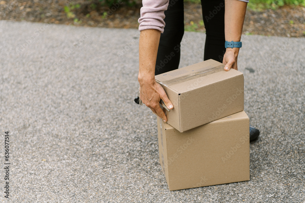 middle aged woman picking up boxes in her driveway Stock Photo | Adobe ...