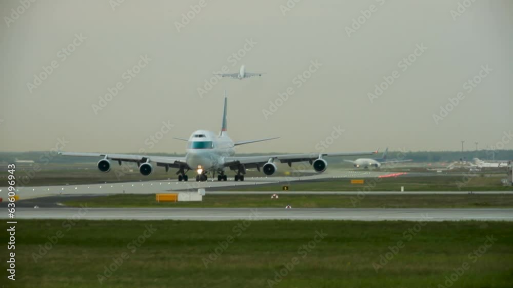 Telephoto approaching cargo airplane on runway and starting plane on ...