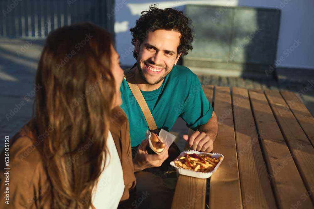 A young man and woman share laughter as they enjoy their fast food ...