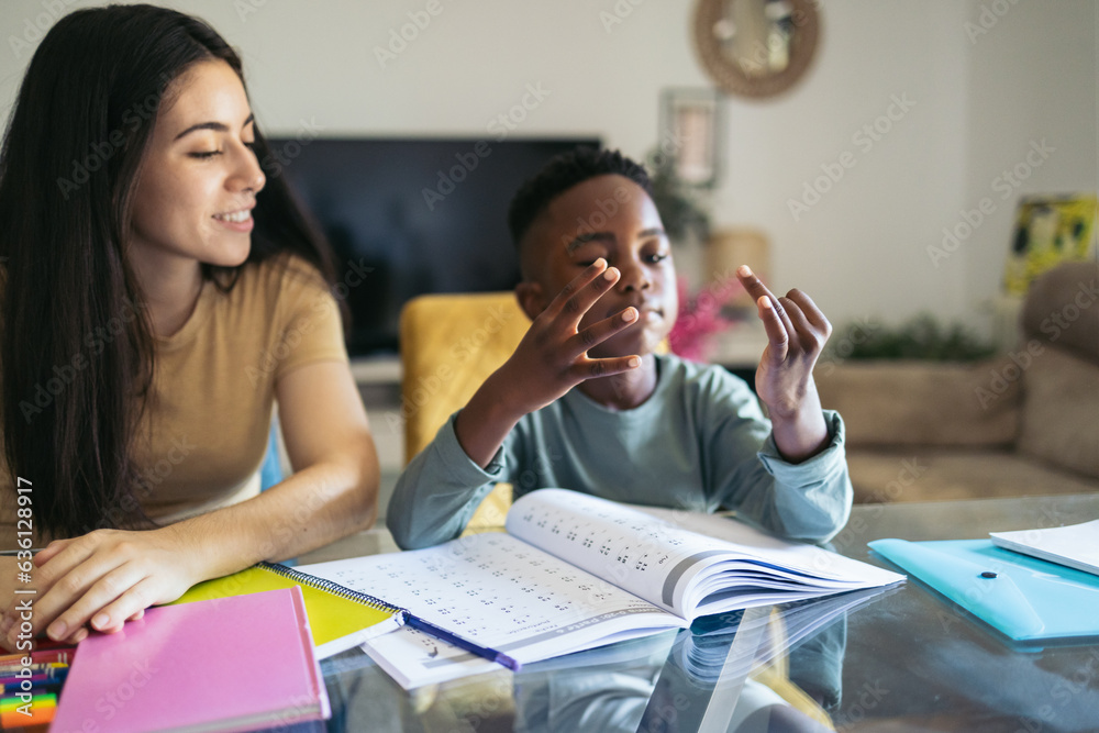 Little boy counting with his fingers while doing his math homework ...
