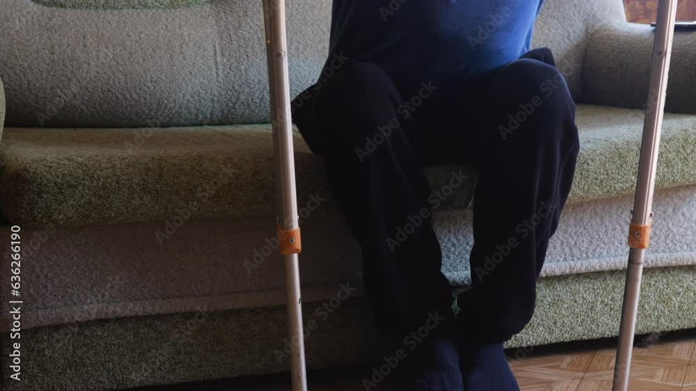 an impersonal man with a leg injury after surgery gets up with crutches ...